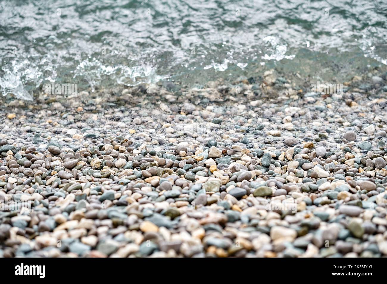 Crystal clean water washes pebbles lying on beach of sea. Wet pebbles ...