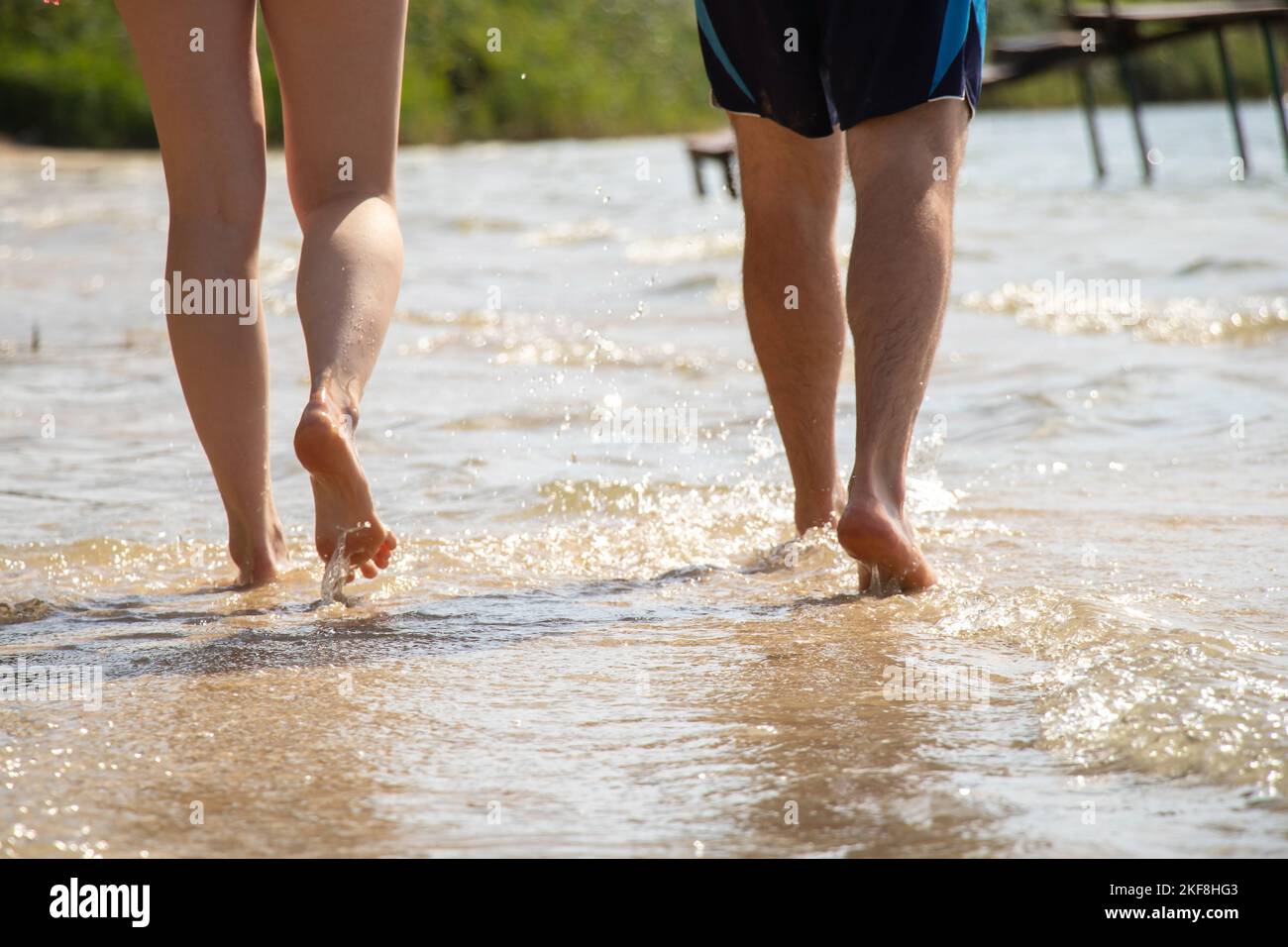 male and female feet in sea water bottom view in the sun in summer ...