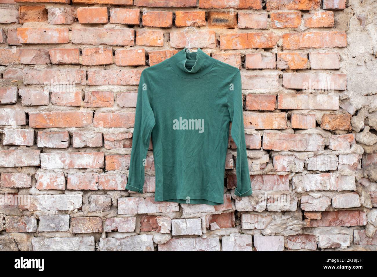 green womens jacket hanging on a brick old wall outside in the sun ...