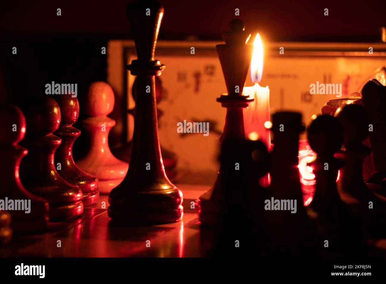 chess pieces stand on a chessboard and clock and next to a burning ...