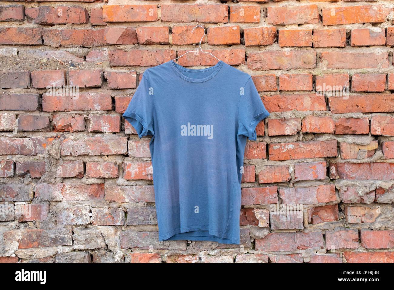 dark blue jacket hanging on a hanger on an old brick wall in the street ...