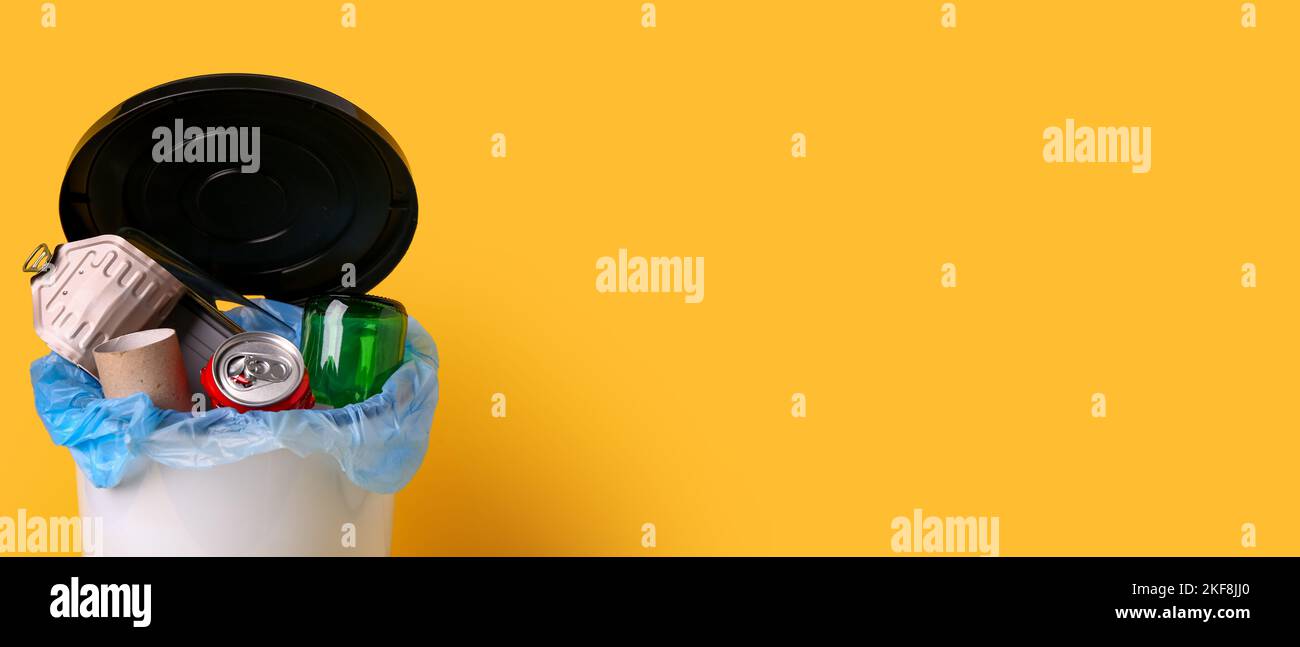 Open trash bin with garbage on yellow background with space for text ...