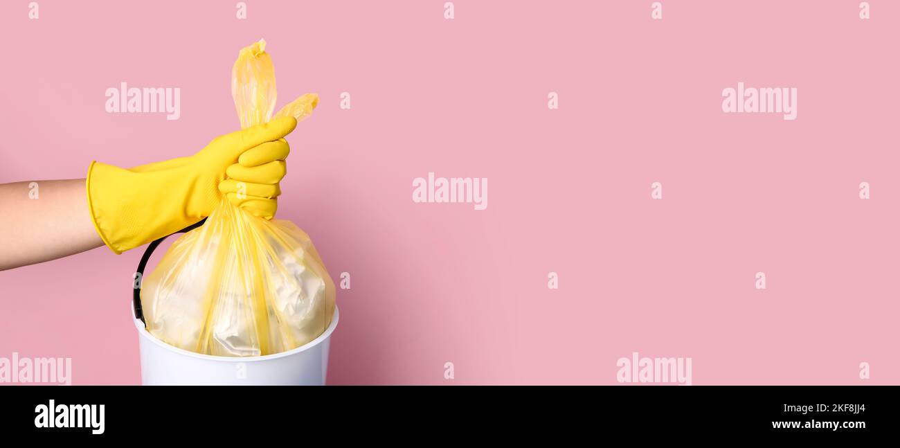 Janitor taking bag with trash out of bin on pink background with space ...