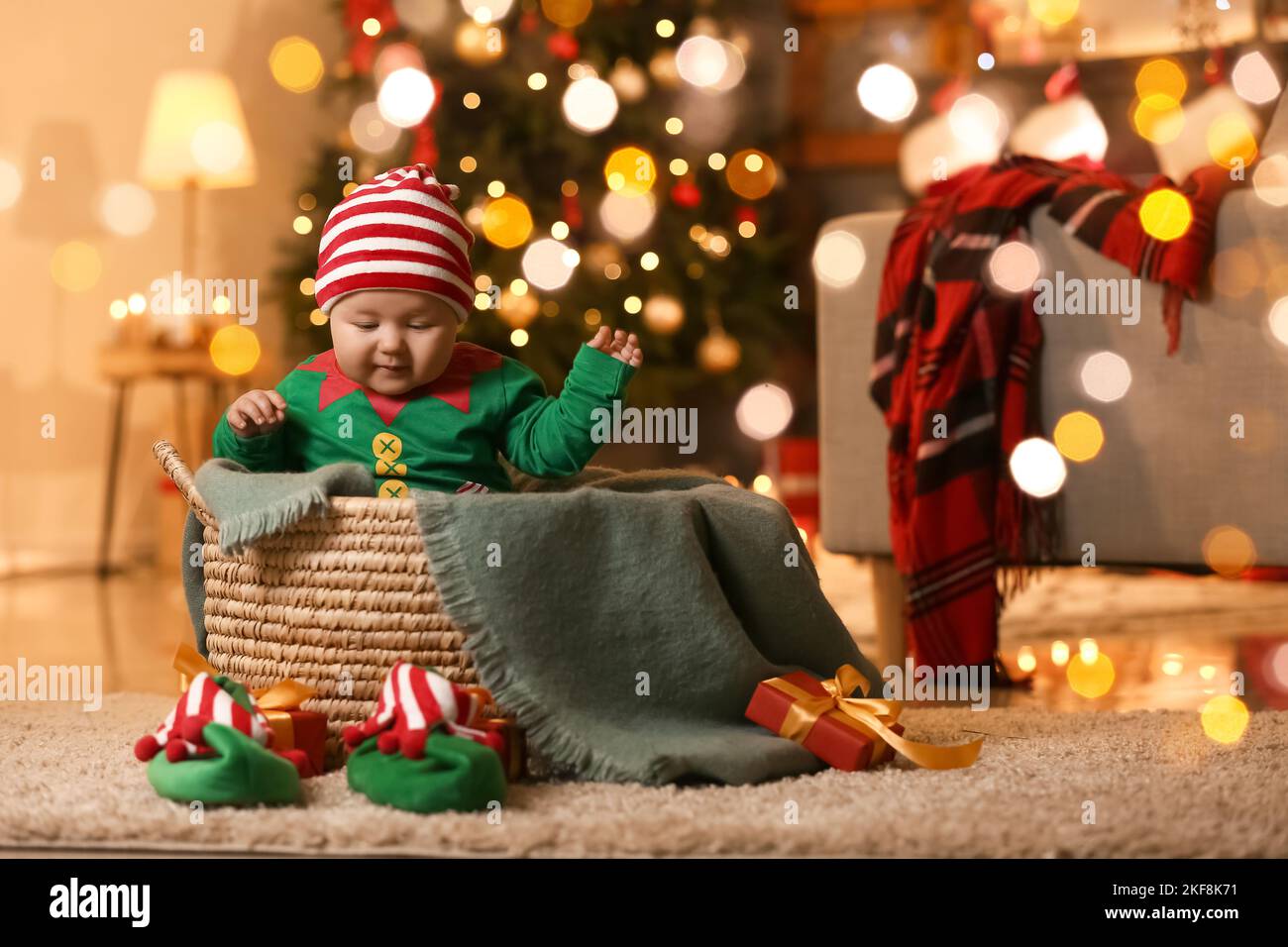 Cute little baby dressed as elf sitting in basket at home on Christmas ...