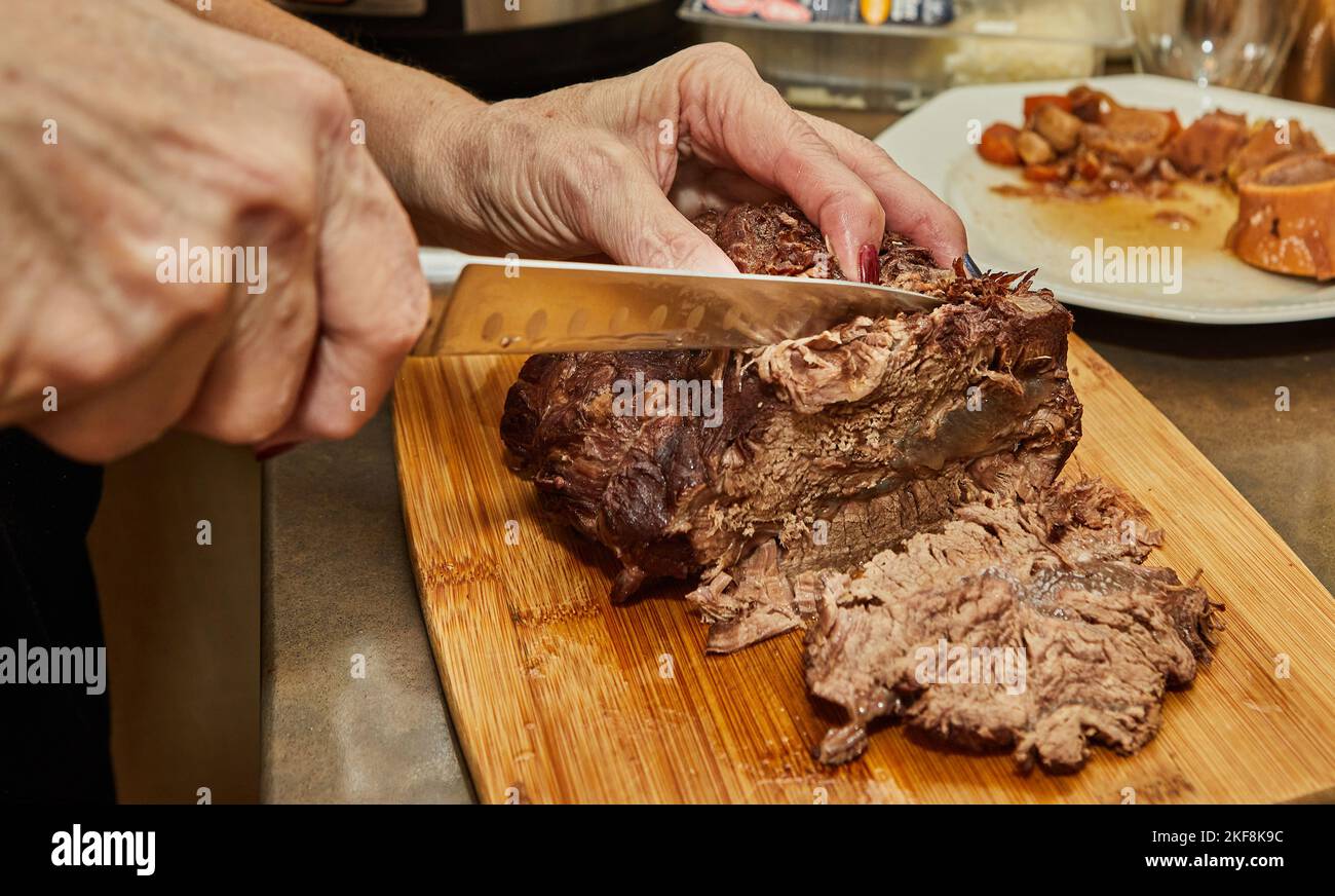 Chef cuts slices from piece of long-cooked beef Stock Photo - Alamy