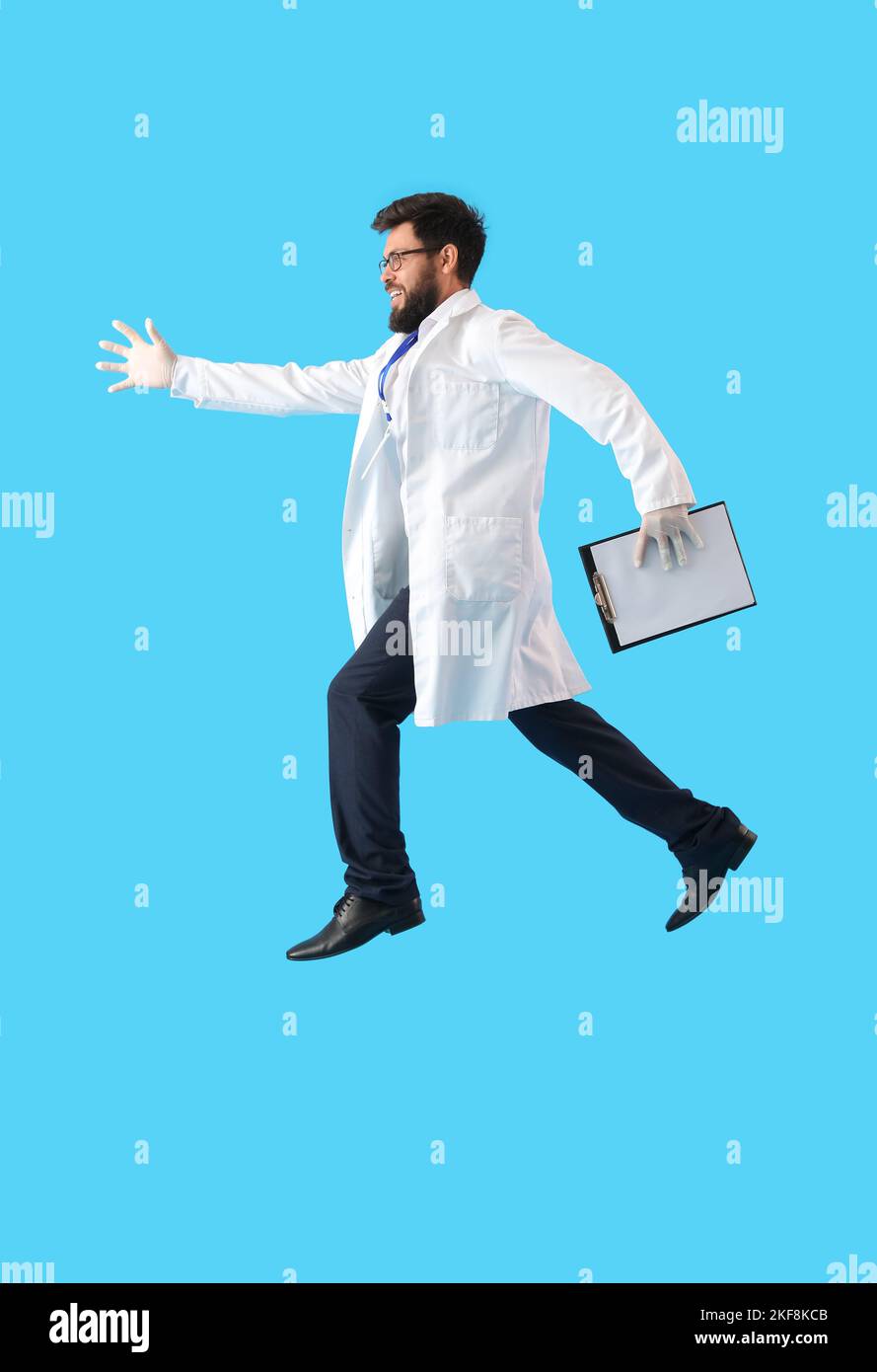 Male doctor with clipboard jumping on blue background Stock Photo - Alamy