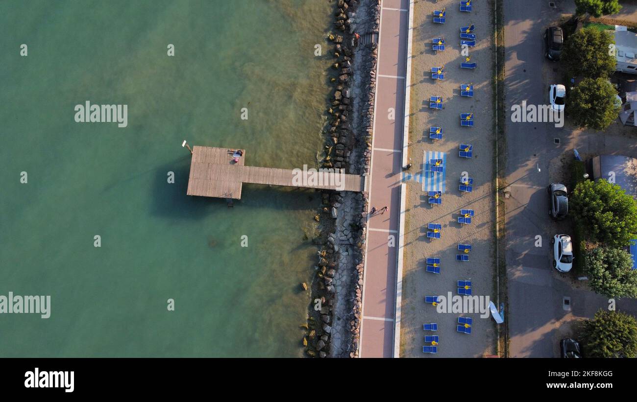 An aerial top view of beach benches against a wooden pier on a sea on a ...