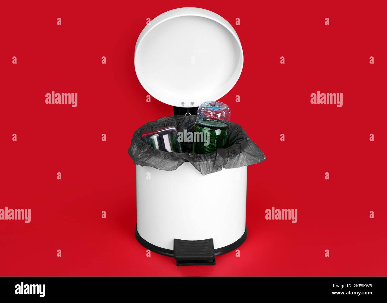 Open rubbish bin with trash on red background Stock Photo - Alamy
