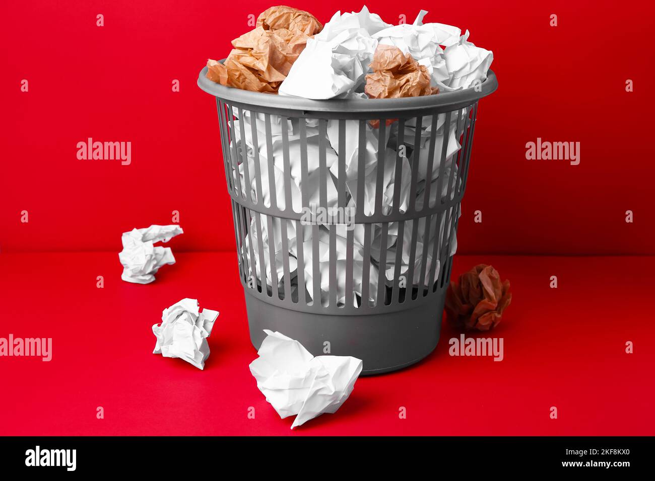 Office bin with crumpled paper on red background Stock Photo - Alamy