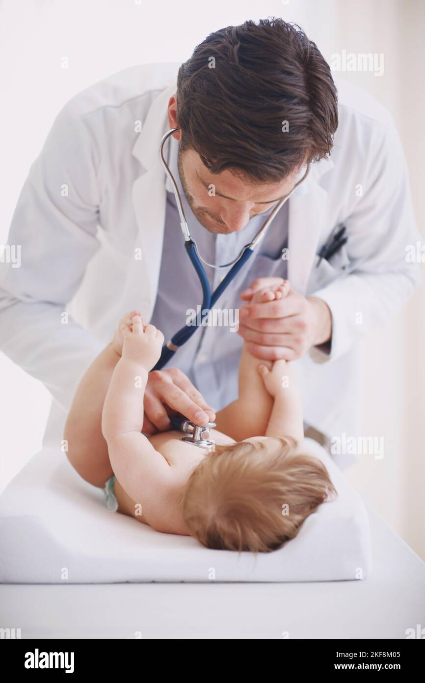 He works so well with his little patients. A male doctor examining an ...