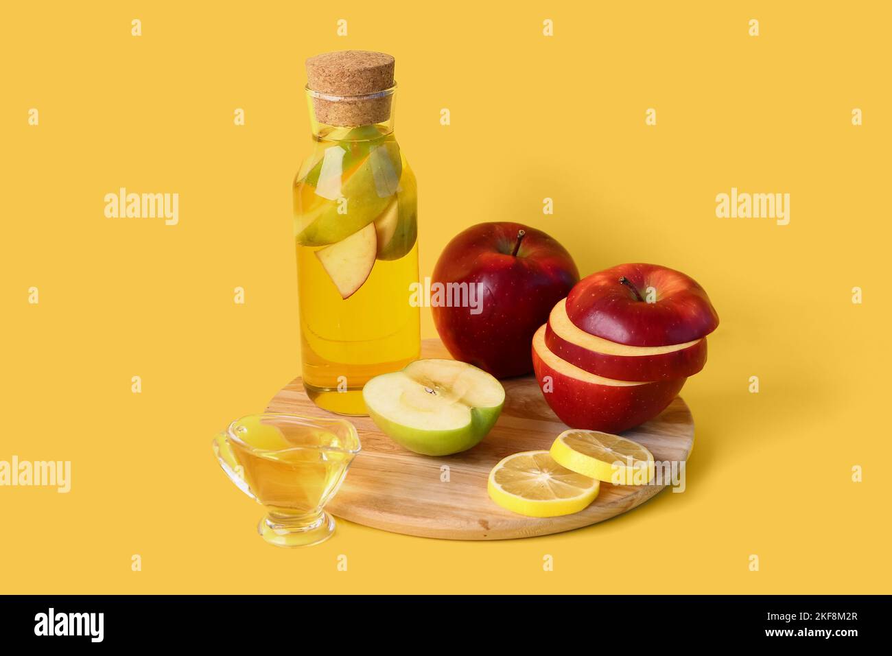 Wooden board with bottle of apple cider vinegar and fresh fruits on ...