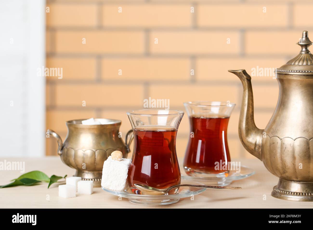Saucer with glass of Turkish tea and dessert on table in room, closeup ...