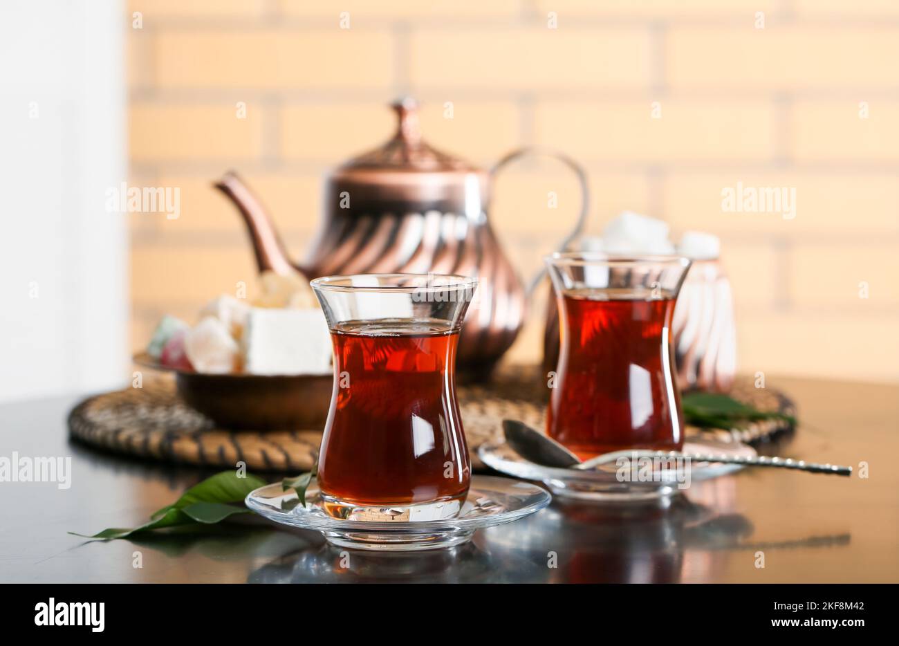 Saucer with glass of Turkish tea and leaf on table in room, closeup ...