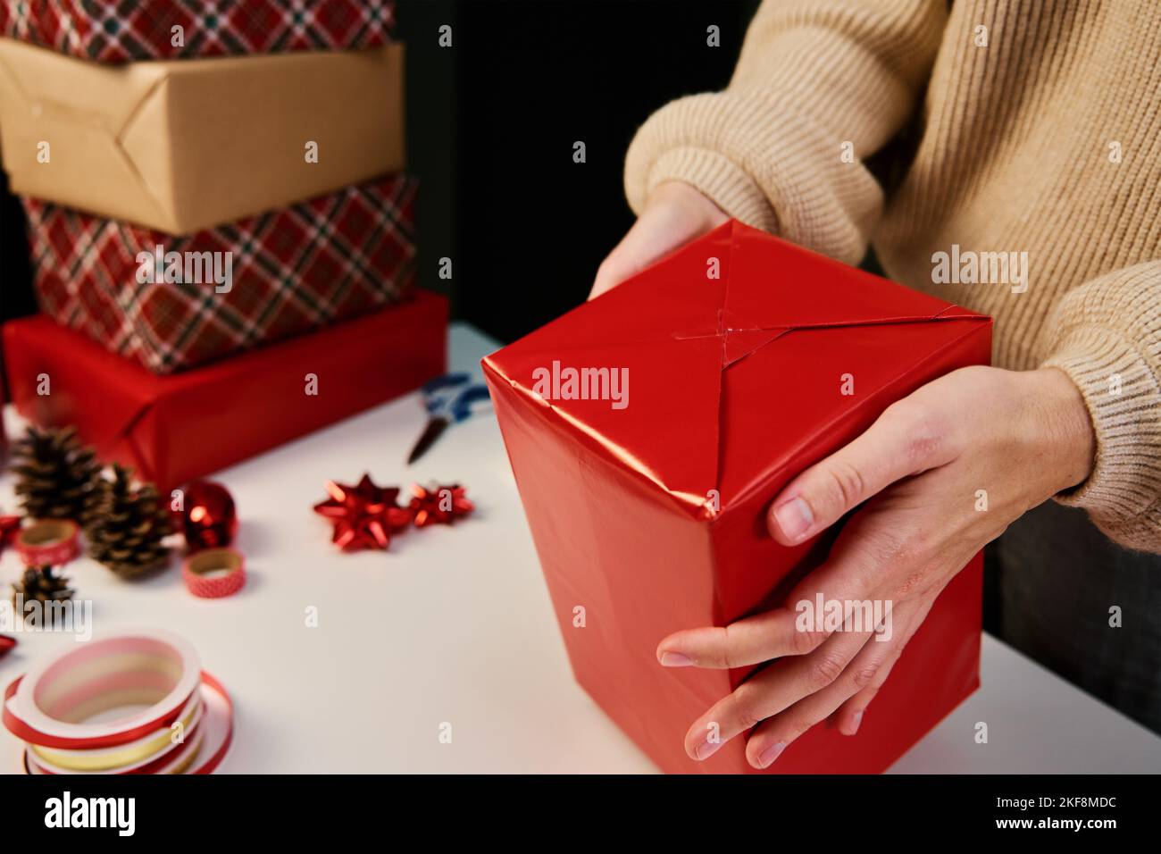 Woman in warm sweater packaging gift box with craft paper. Present for ...