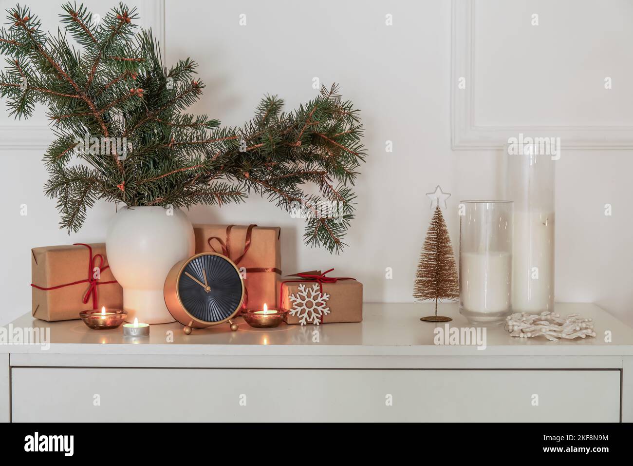 Alarm clock, candles, Christmas presents and vase with fir branches on ...