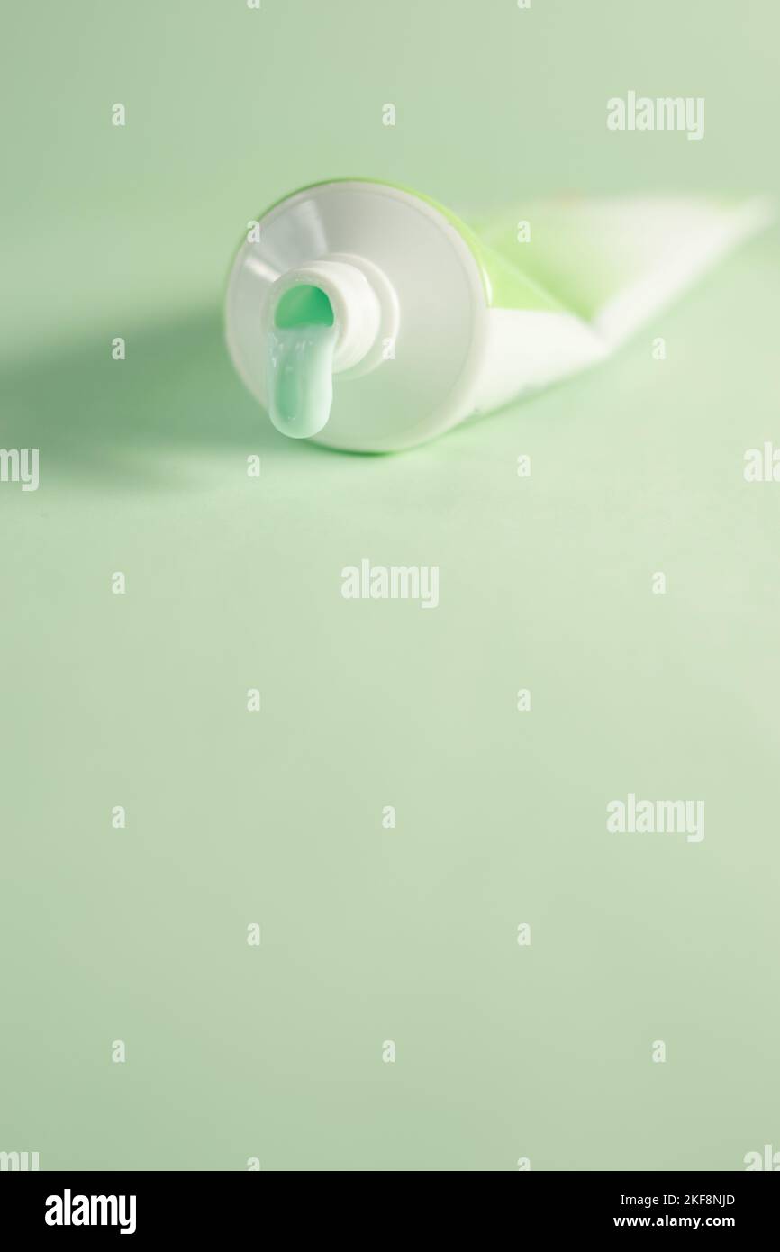 A dripping mint toothpaste tube isolated on green background - the ...