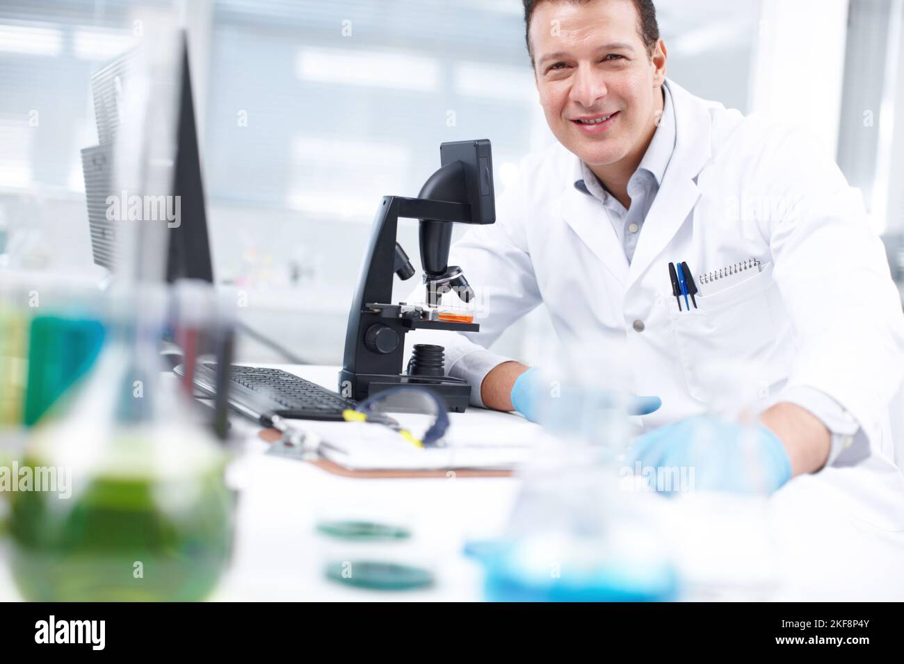 Research saves lives. A researcher smiling while sitting at a table in ...