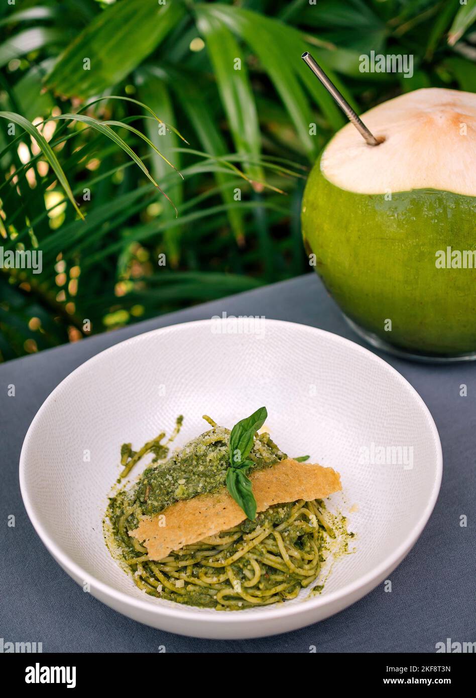Spaghetti with pesto and coconut under palm tree Stock Photo - Alamy