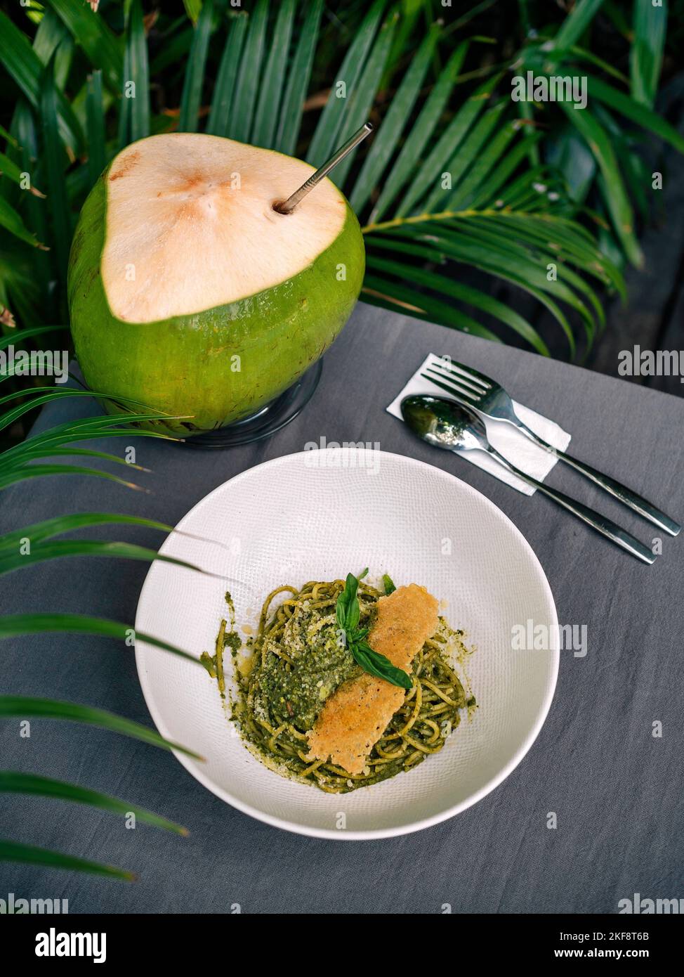 Spaghetti with pesto and coconut under palm tree Stock Photo - Alamy