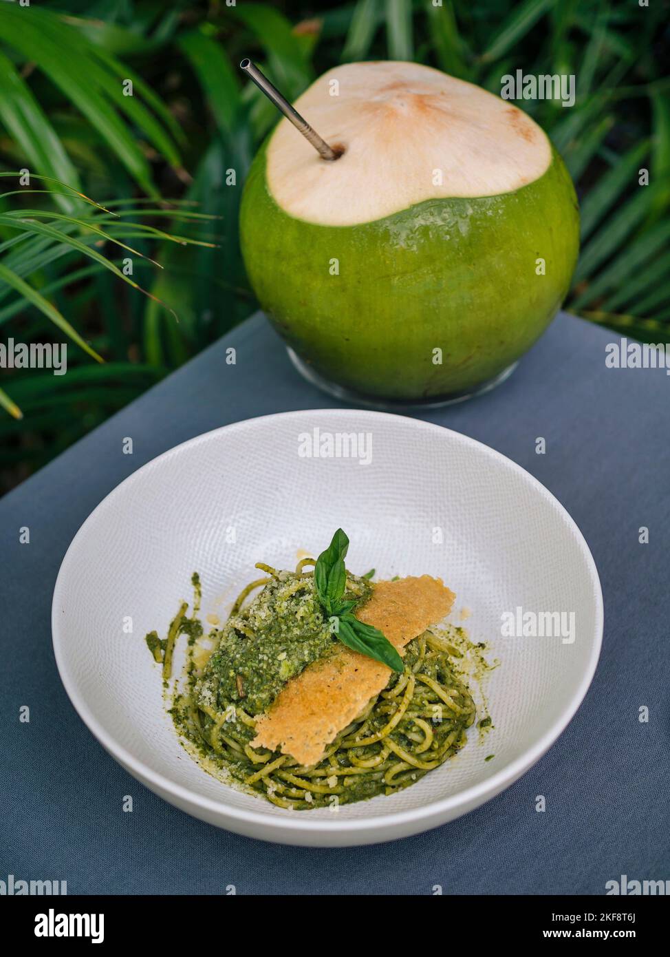 Spaghetti with pesto and coconut under palm tree Stock Photo - Alamy
