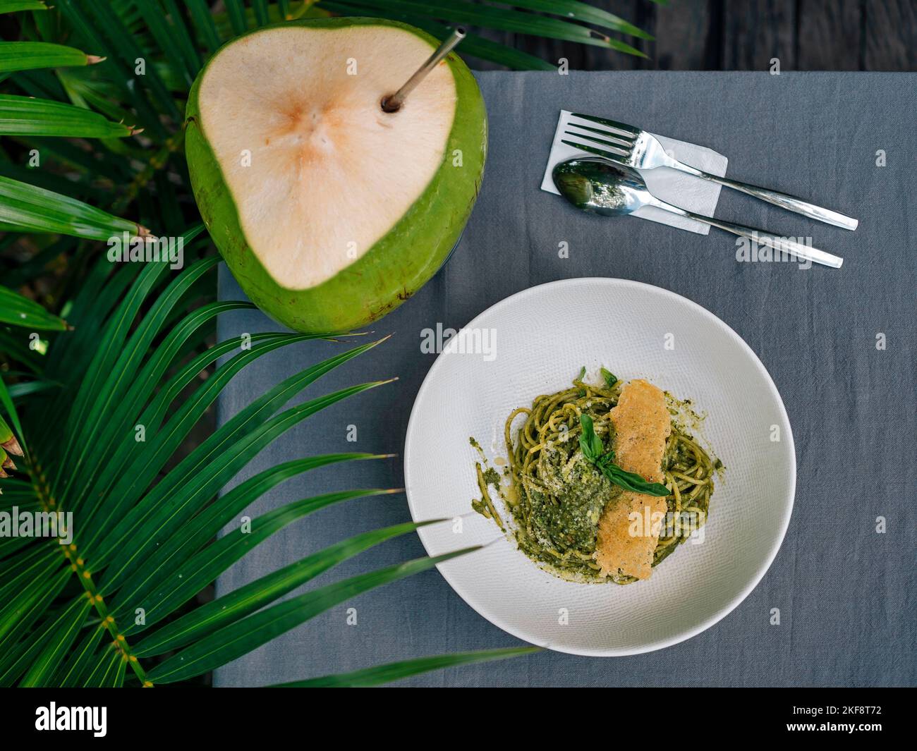 Spaghetti with pesto and coconut under palm tree Stock Photo - Alamy