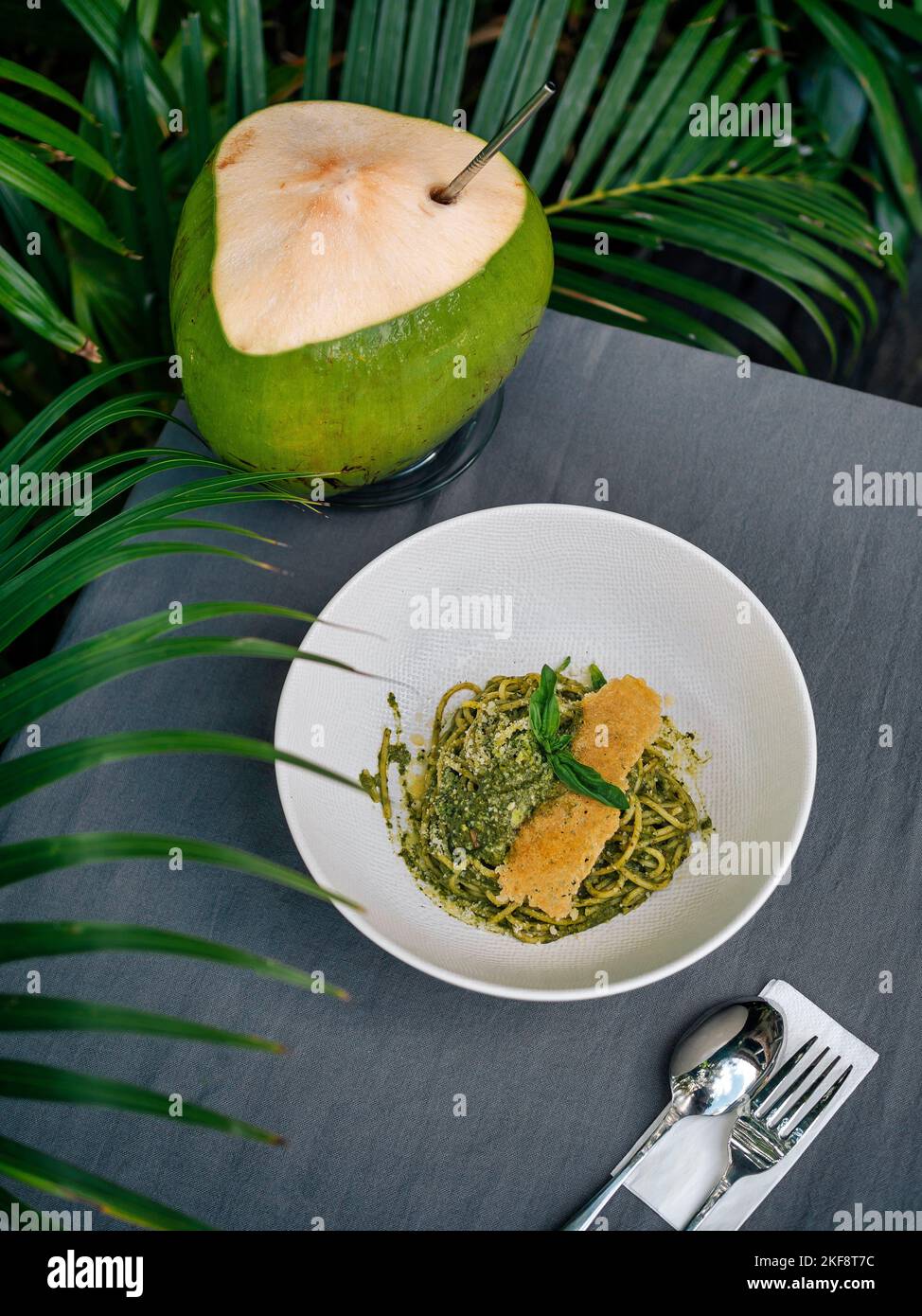 Spaghetti with pesto and coconut under palm tree Stock Photo - Alamy