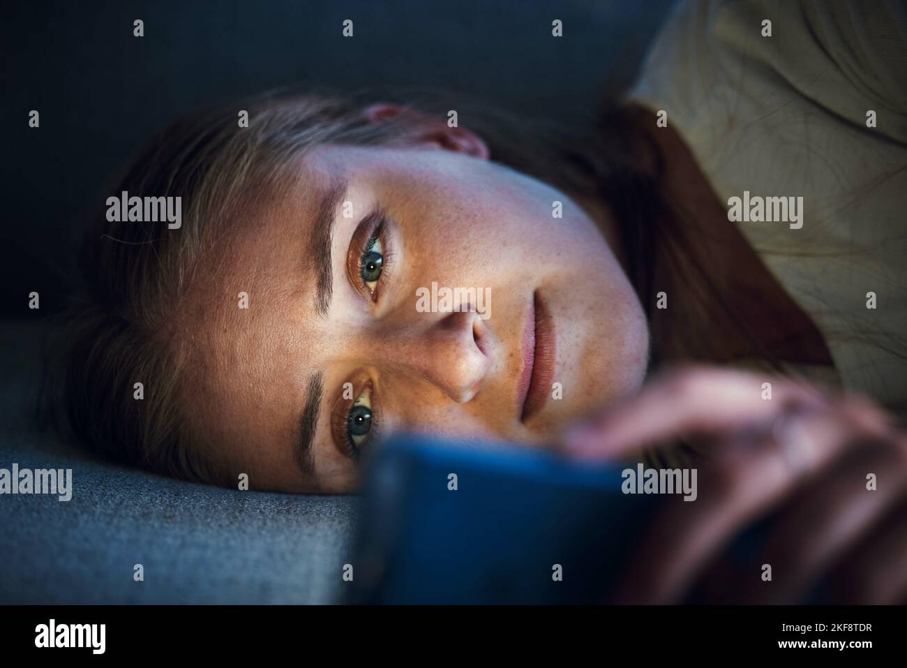 Night, phone and young woman on sofa to check social media, browsing internet and online content ...