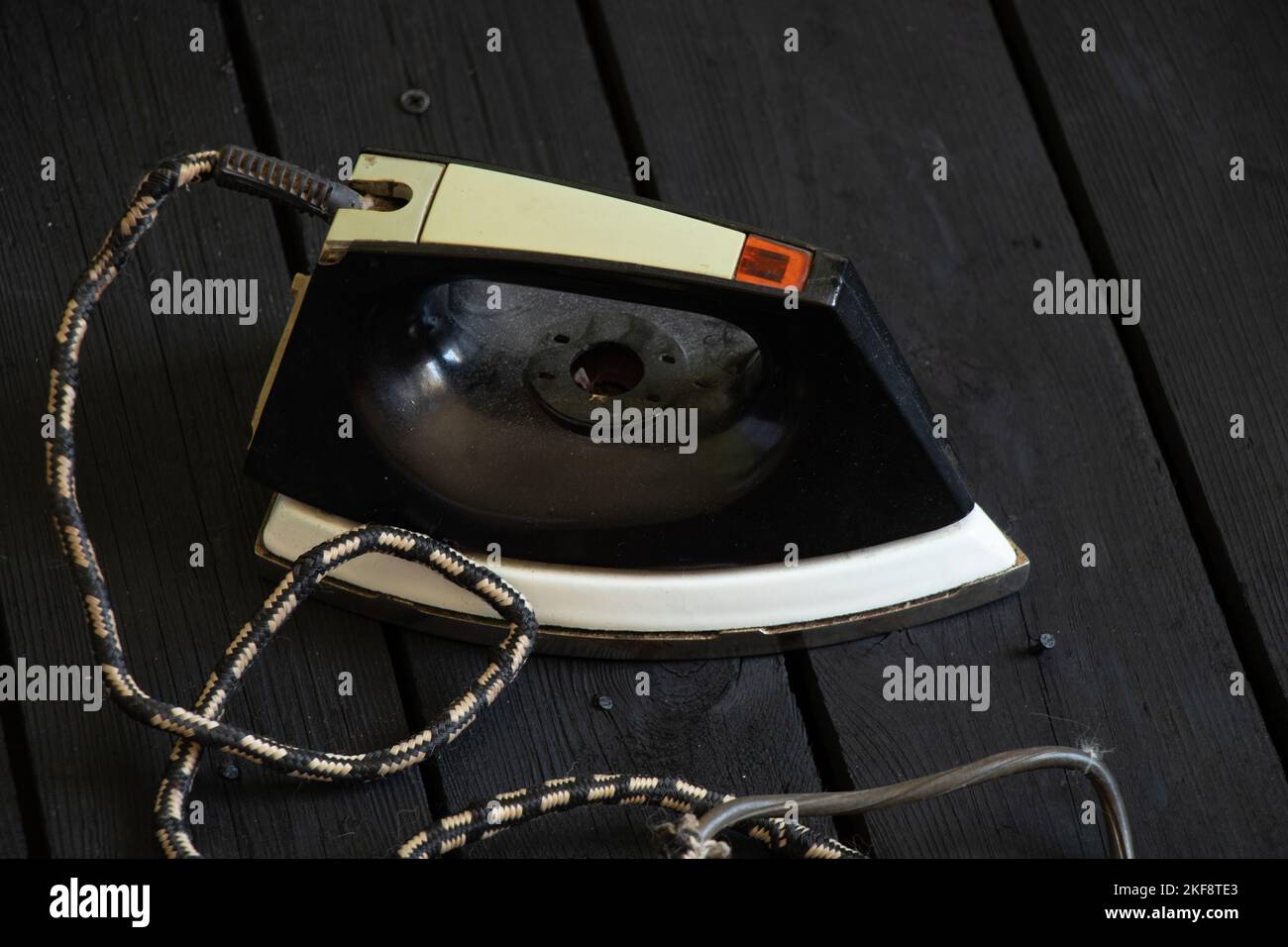 an old electric iron stands on a black wooden floor, a soviet iron ...