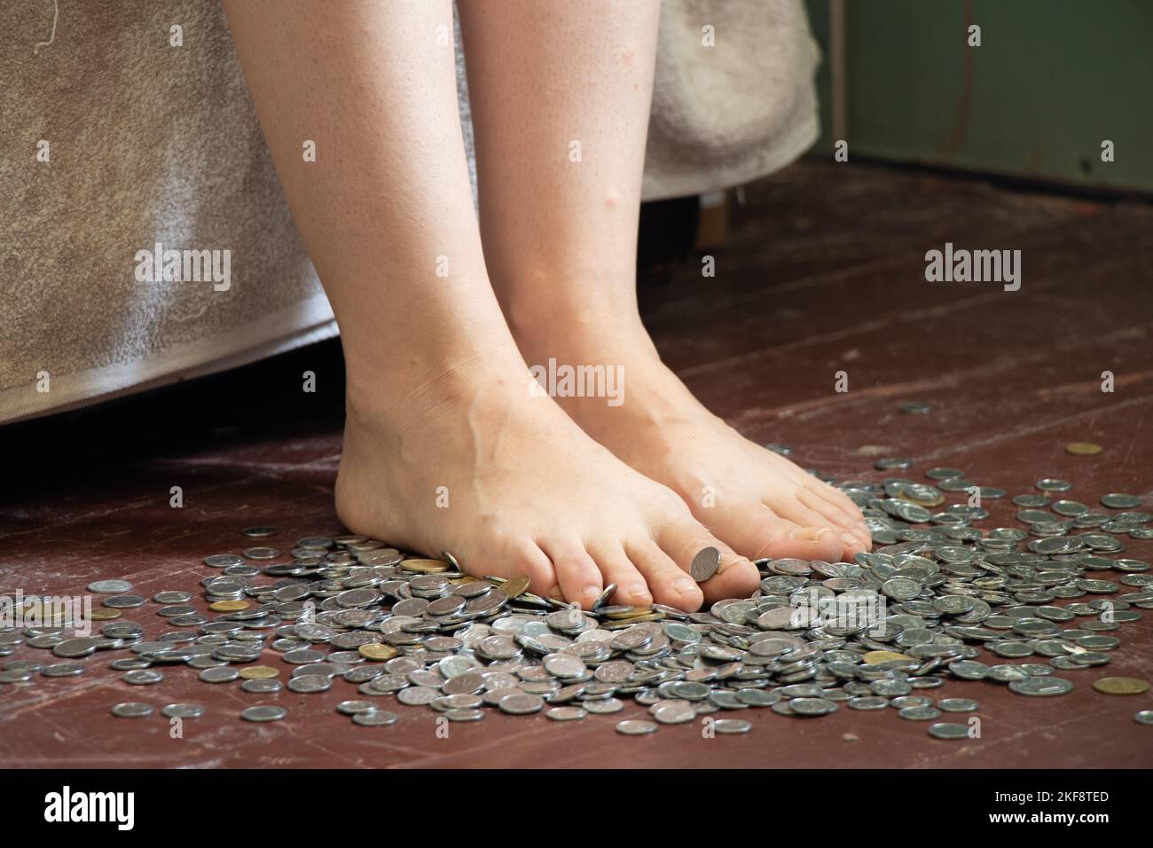 female feet stand on Ukrainian small coins on the floor of the house ...