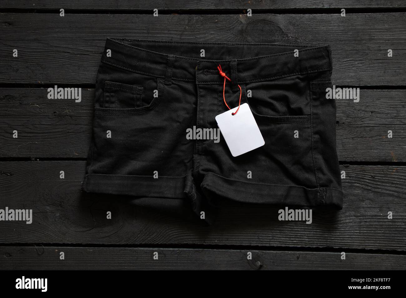 womens denim shorts with white blank paper price tag for text on table ...