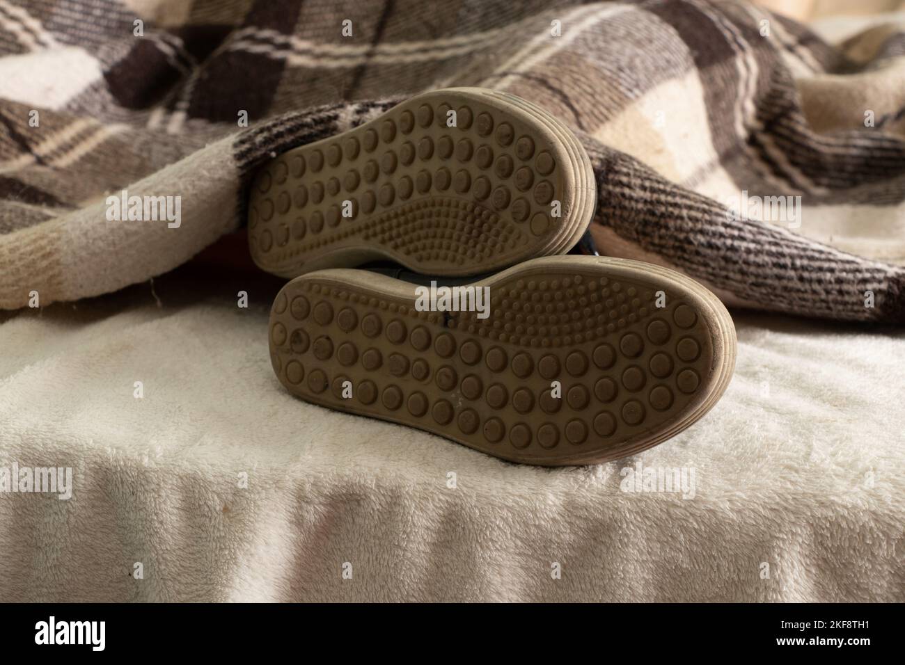 a girl in sneakers sleeps on a bed at home, her feet are in shoes on ...