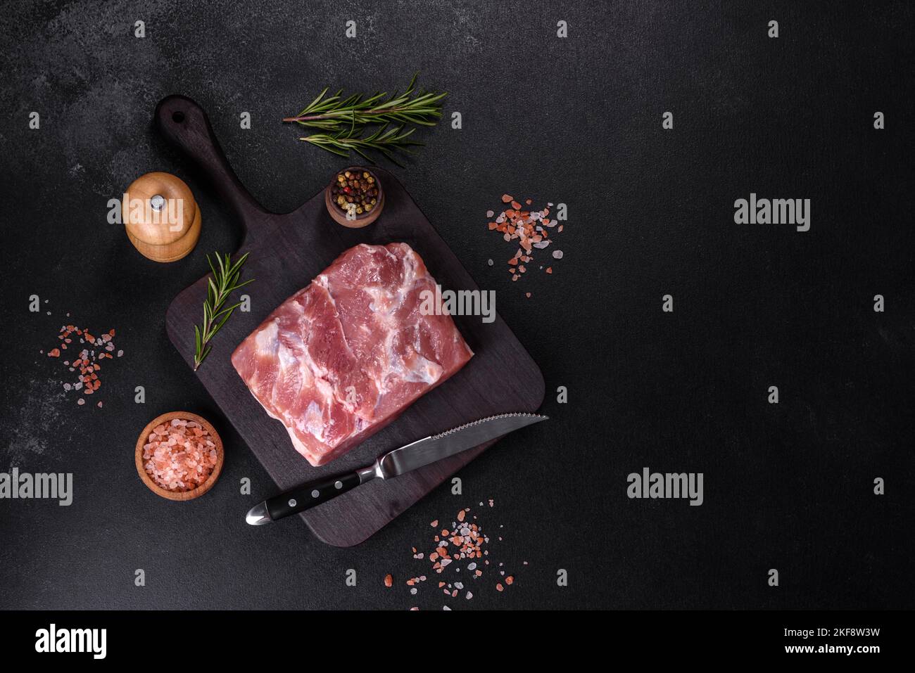 Fresh piece of raw pork with spices, salt and herbs on a wooden cutting ...
