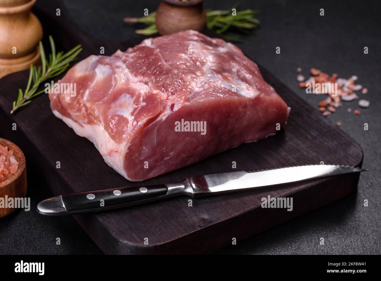 Fresh piece of raw pork with spices, salt and herbs on a wooden cutting ...
