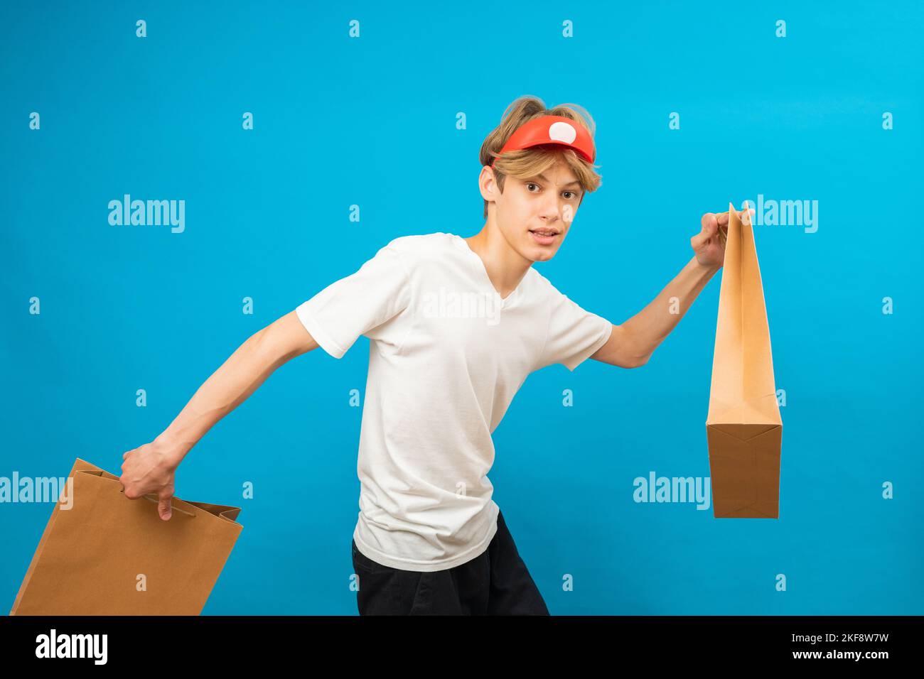 Harry up. Young seller in casual white t-shirt with paper bag running ...