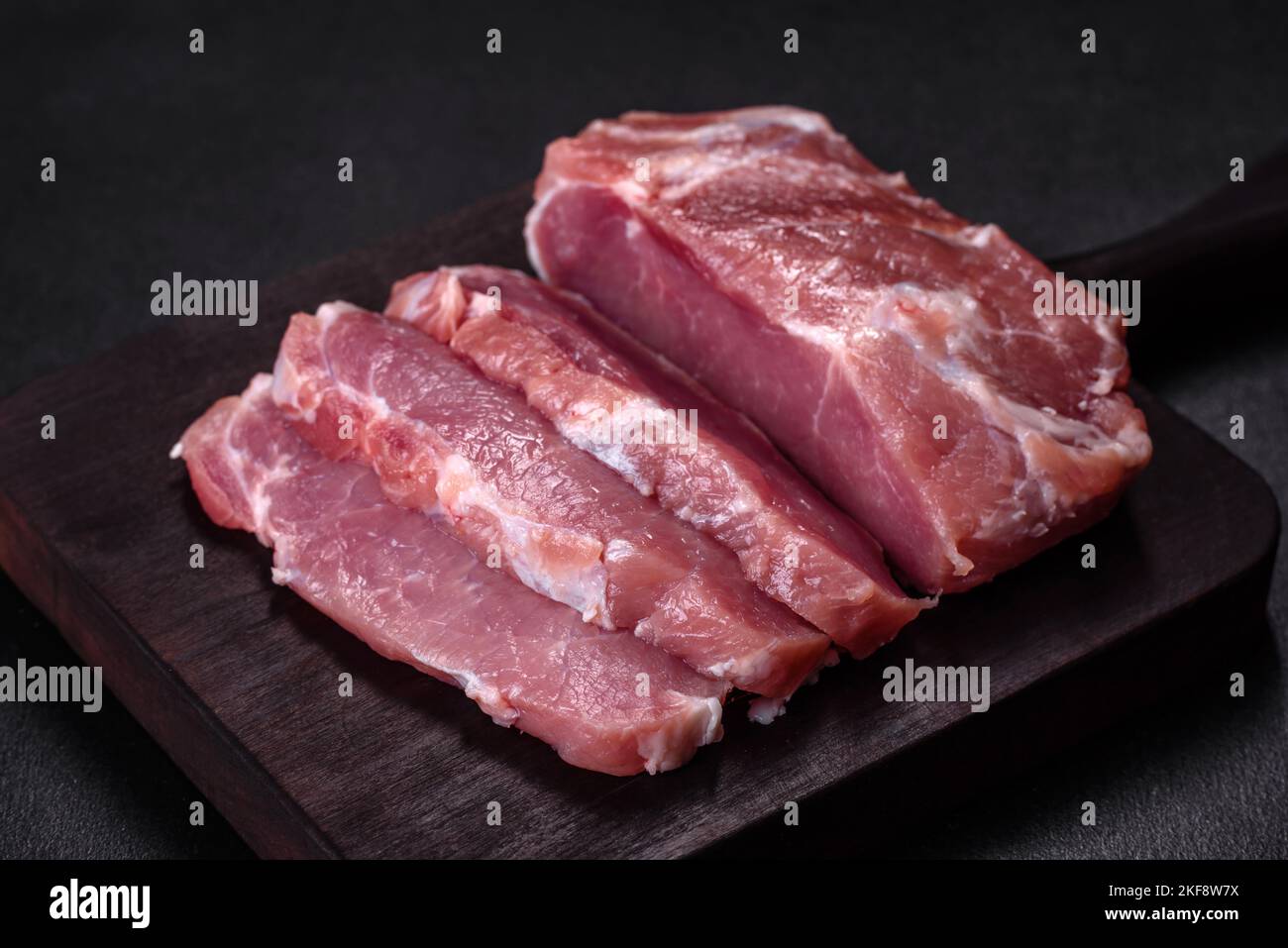 Fresh piece of raw pork with spices, salt and herbs on a wooden cutting ...