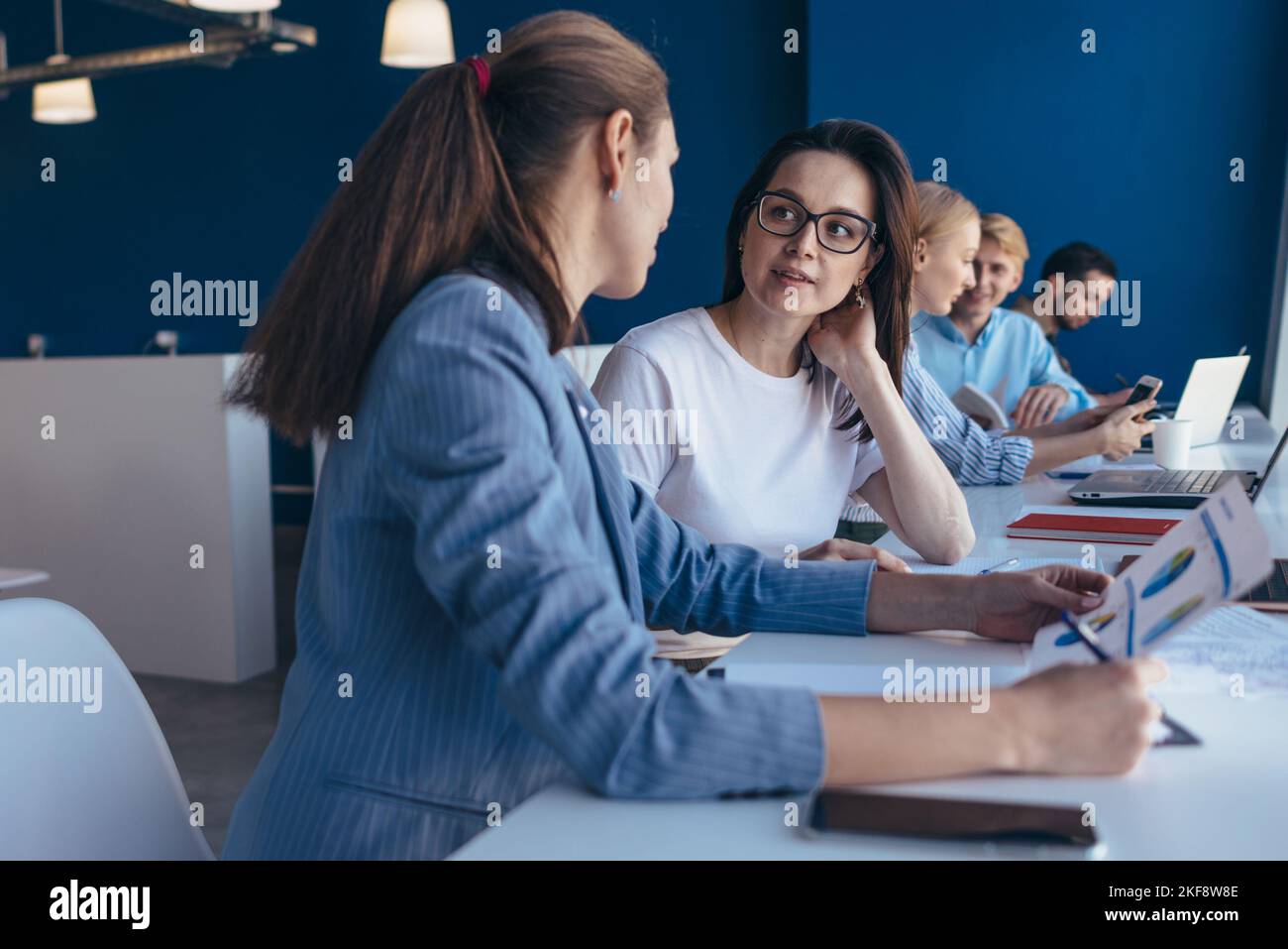 Office workers talking while sitting at a desk Stock Photo - Alamy