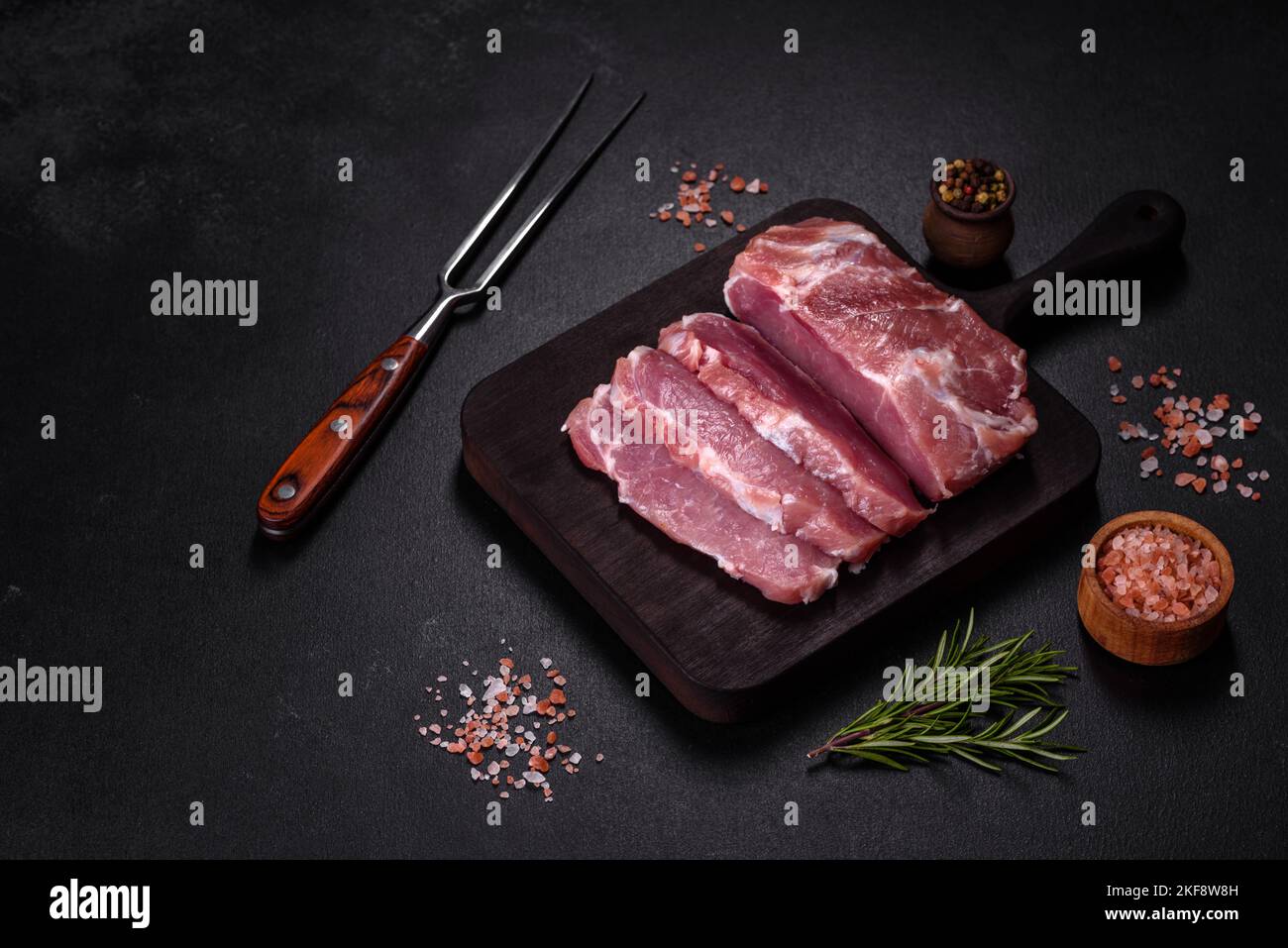 Fresh piece of raw pork with spices, salt and herbs on a wooden cutting ...