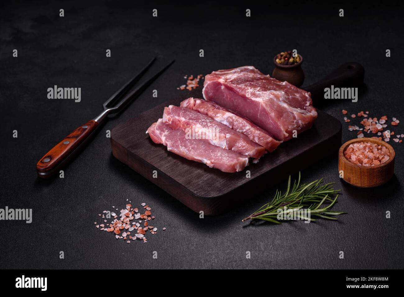 Fresh piece of raw pork with spices, salt and herbs on a wooden cutting ...
