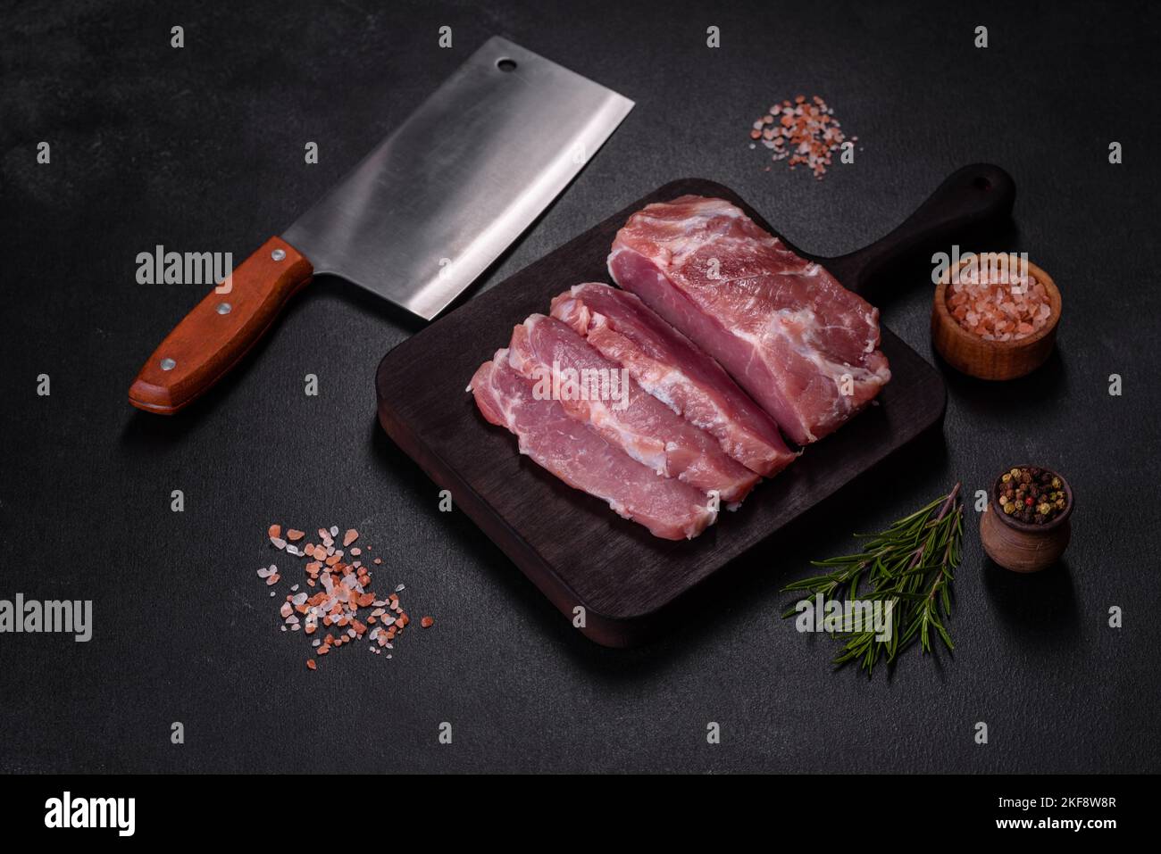 Fresh piece of raw pork with spices, salt and herbs on a wooden cutting ...