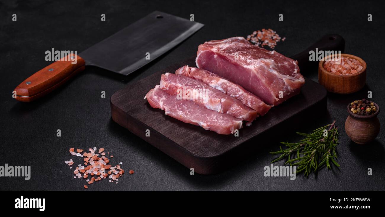 Fresh piece of raw pork with spices, salt and herbs on a wooden cutting ...