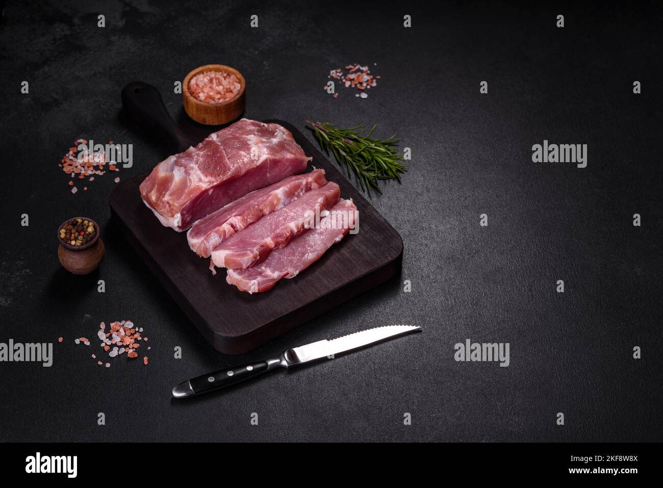 Fresh piece of raw pork with spices, salt and herbs on a wooden cutting ...