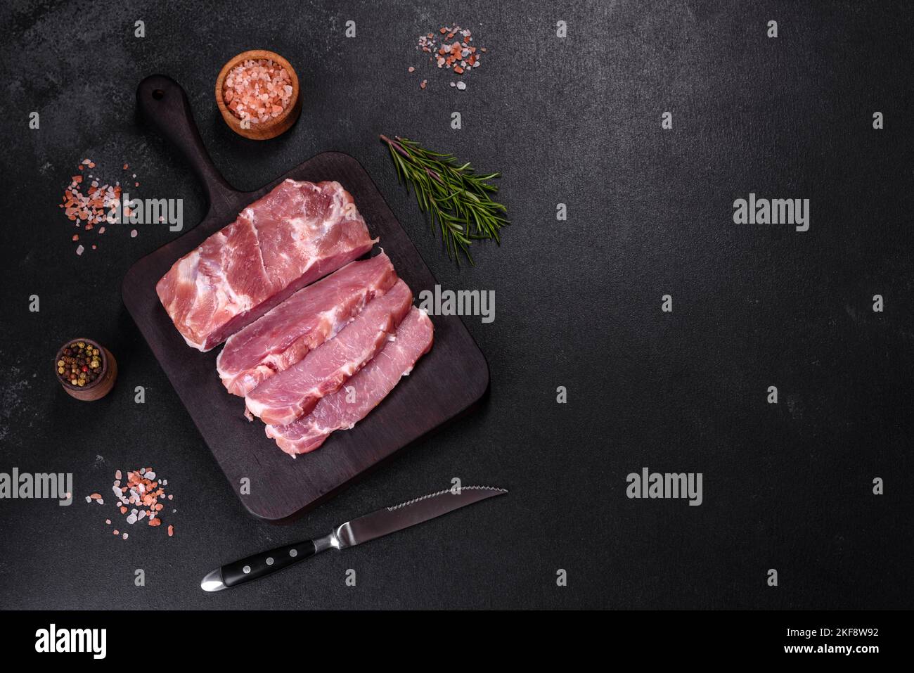 Fresh piece of raw pork with spices, salt and herbs on a wooden cutting ...