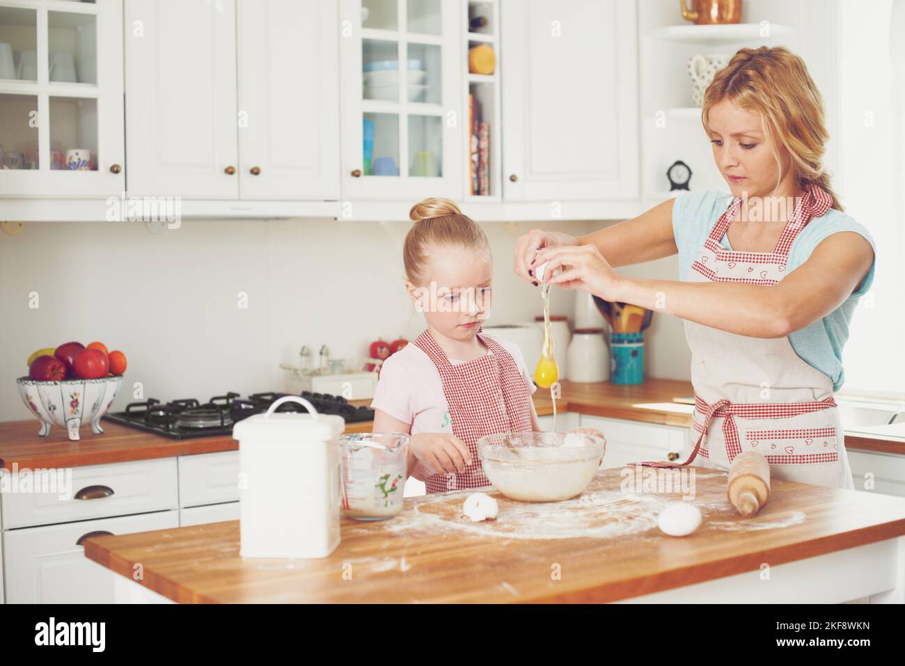 Adding in some eggs...Cute little girl baking in the kitchen with her ...