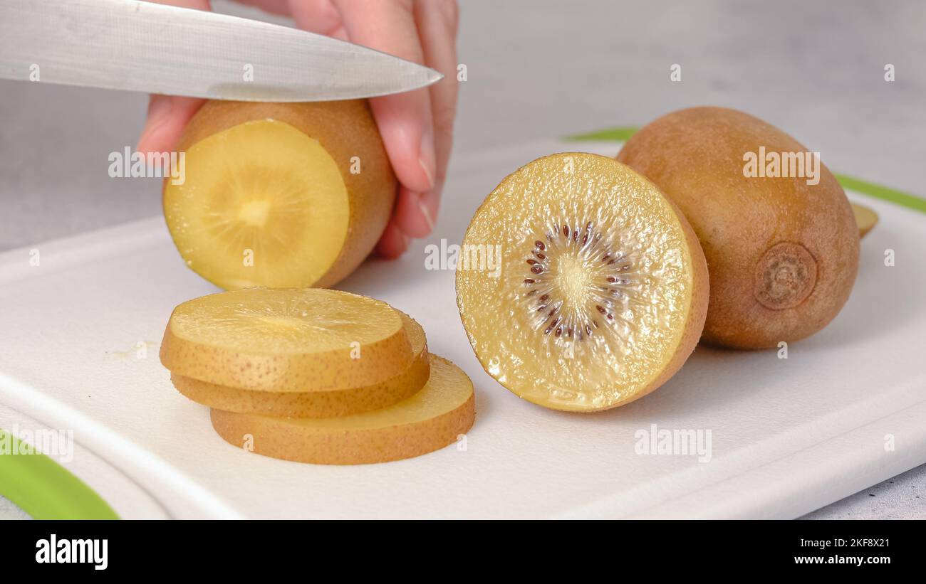 Woman slicing kiwi on cutting board close-up on kitchen table Stock ...