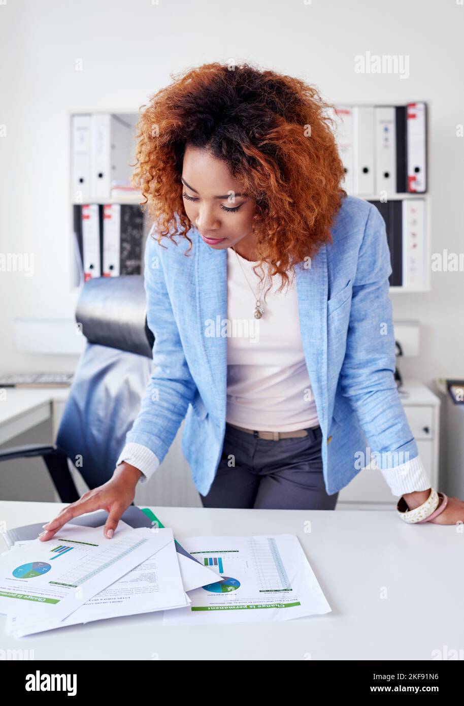Taking a look at the numbers. a young businesswoman going over ...