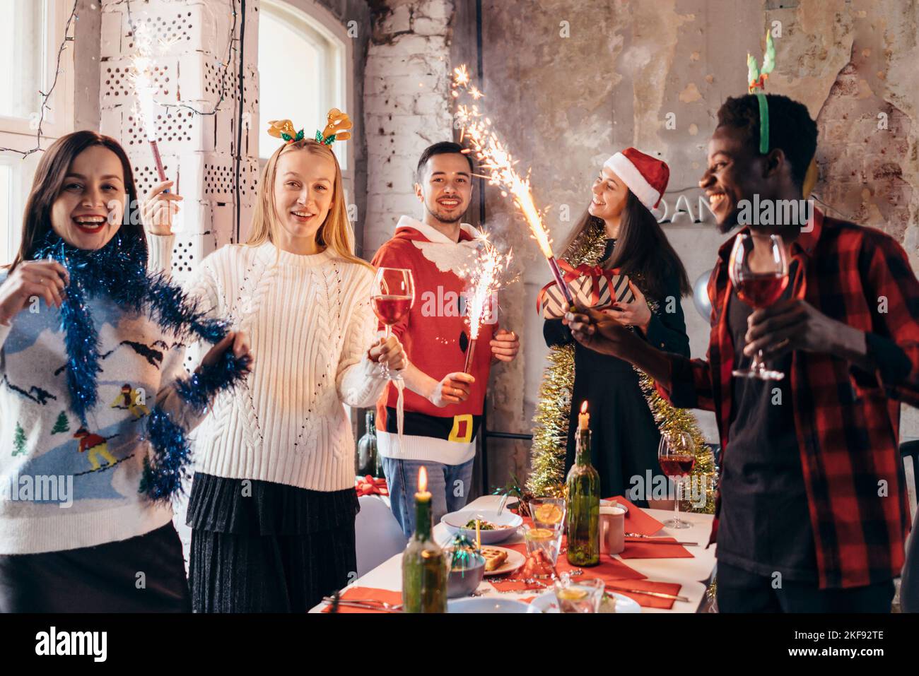 Group of friends making a toast with drinks at Christmas eve party ...