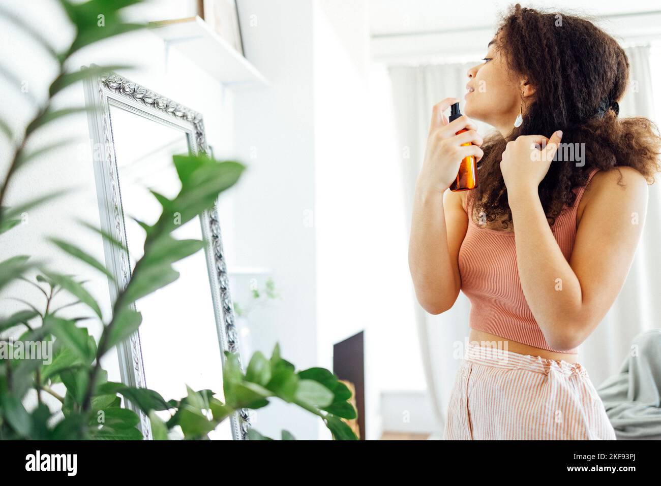 Pretty mixed race Woman Applying Moisturising Spray To Her Curly Hair ...