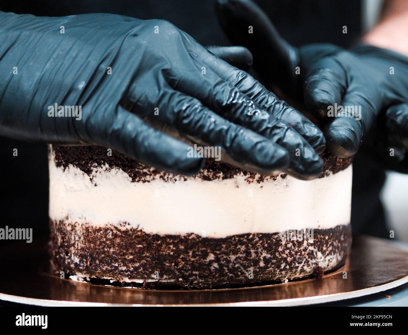 Chef cake designer preparing layered creamy cake base for frosted ...