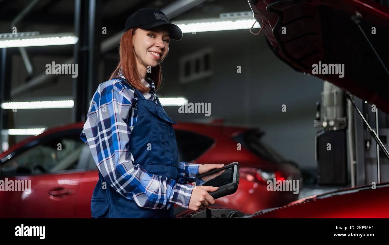 Caucasian female auto mechanic uses a special computer to diagnose ...
