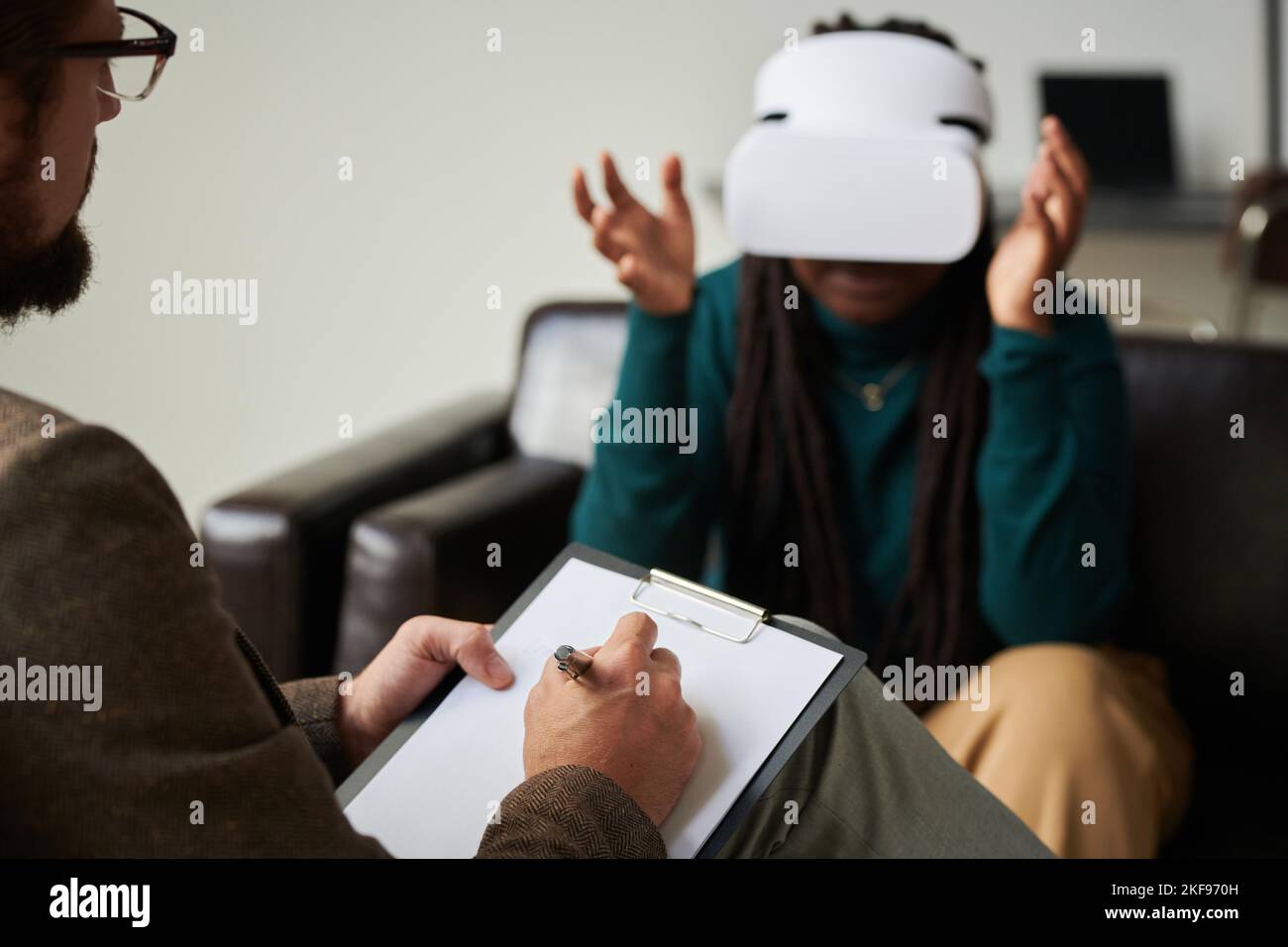 Psychologist making notes while talking to patient in virtual reality ...